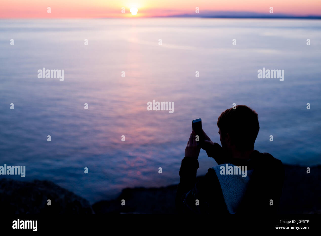 man photographer taking photos of sunset at the sea Stock Photo - Alamy