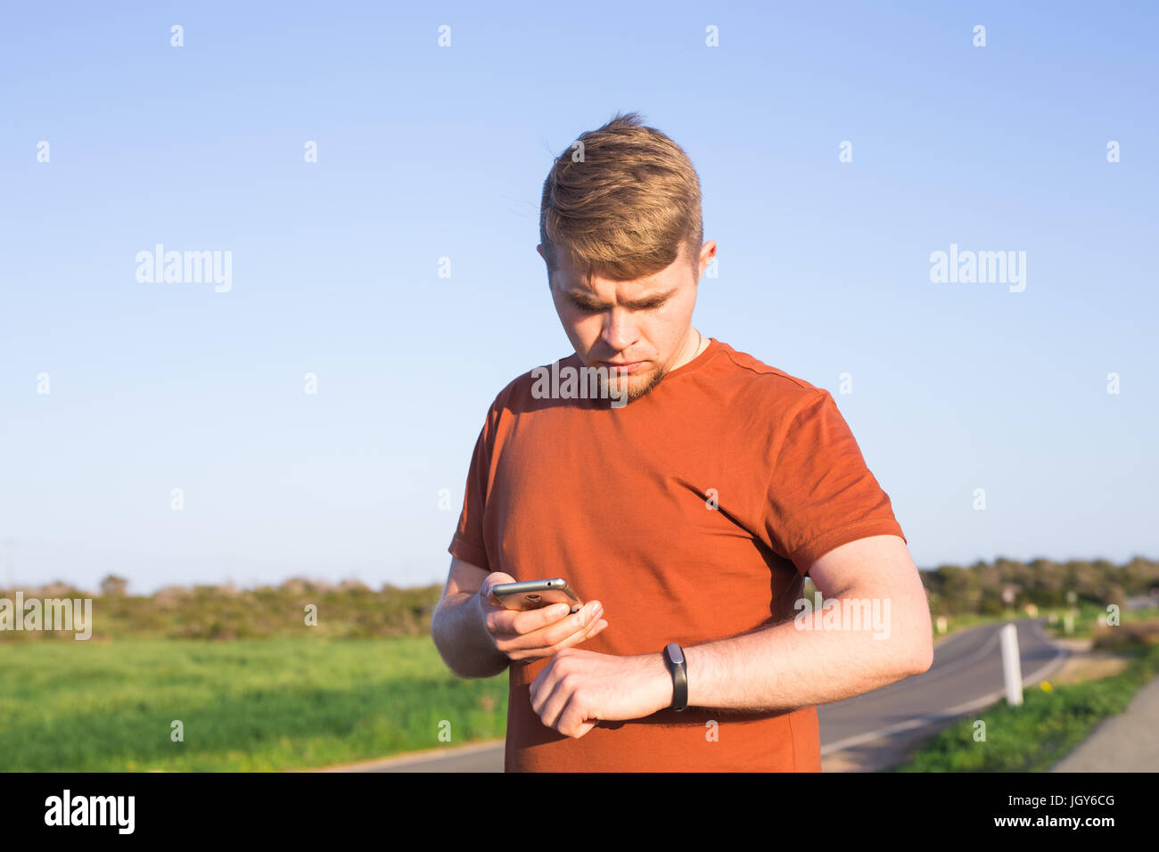 Male runner jogging outside looking at his wearable fitness tracker ...