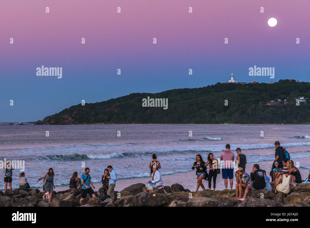People watch the sun set and full moon rise at Byron bay, New South ...