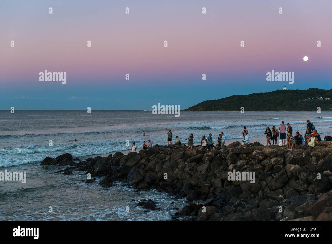 People watch the sun set and full moon rise at Byron bay, New South ...