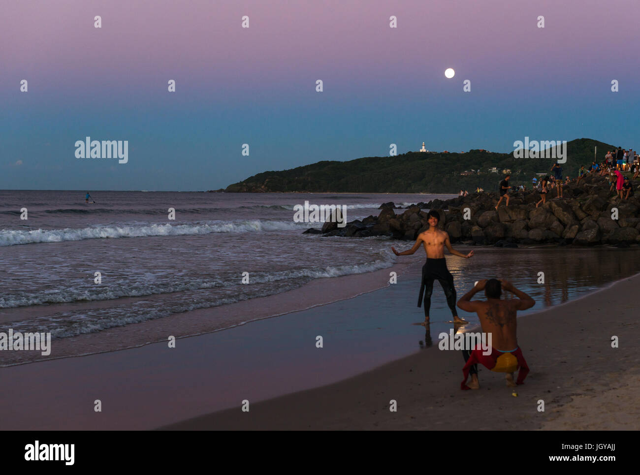 People watch the sun set and full moon rise at Byron bay, New South ...