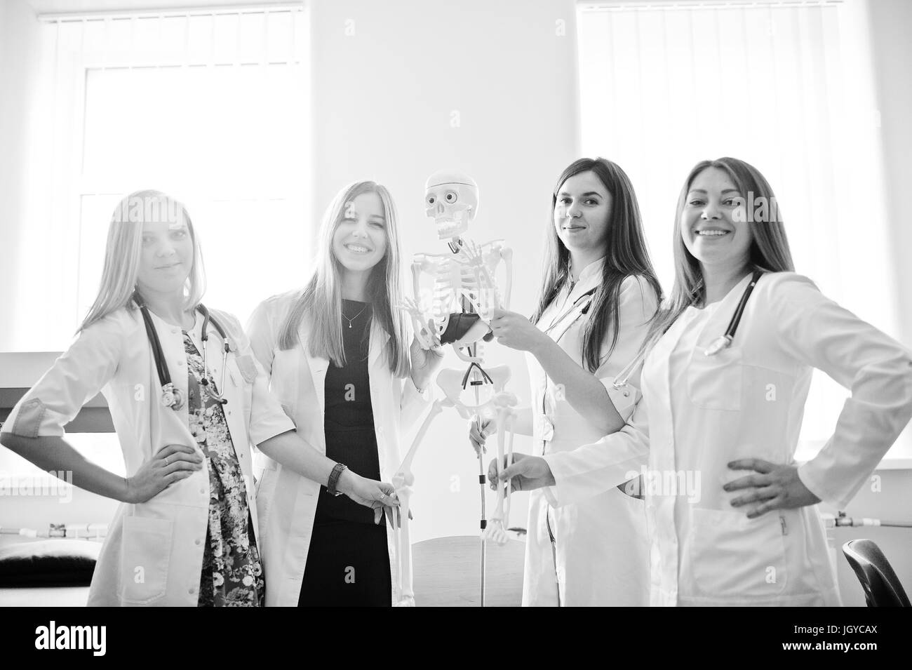 Young doctors having fun by posing with skeleton. Black and white photo ...