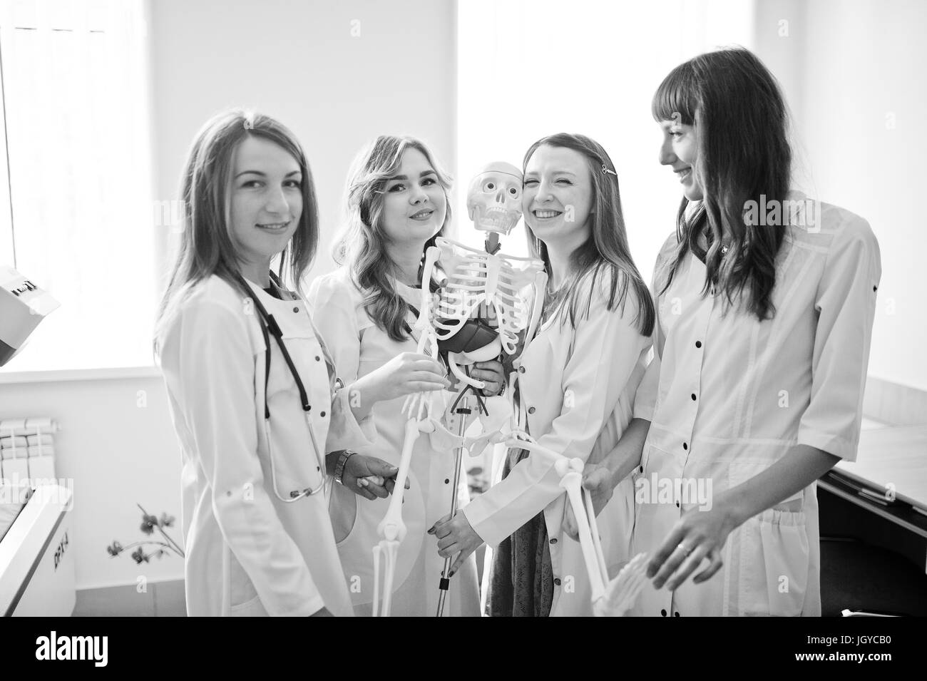 Young doctors having fun by posing with skeleton. Black and white photo ...
