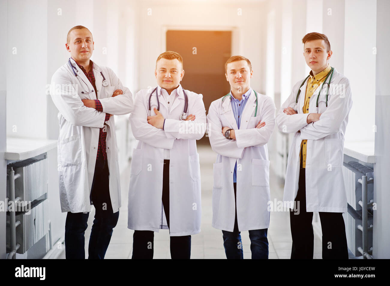 Four confident male doctors in white coats with stethoscopes standing ...