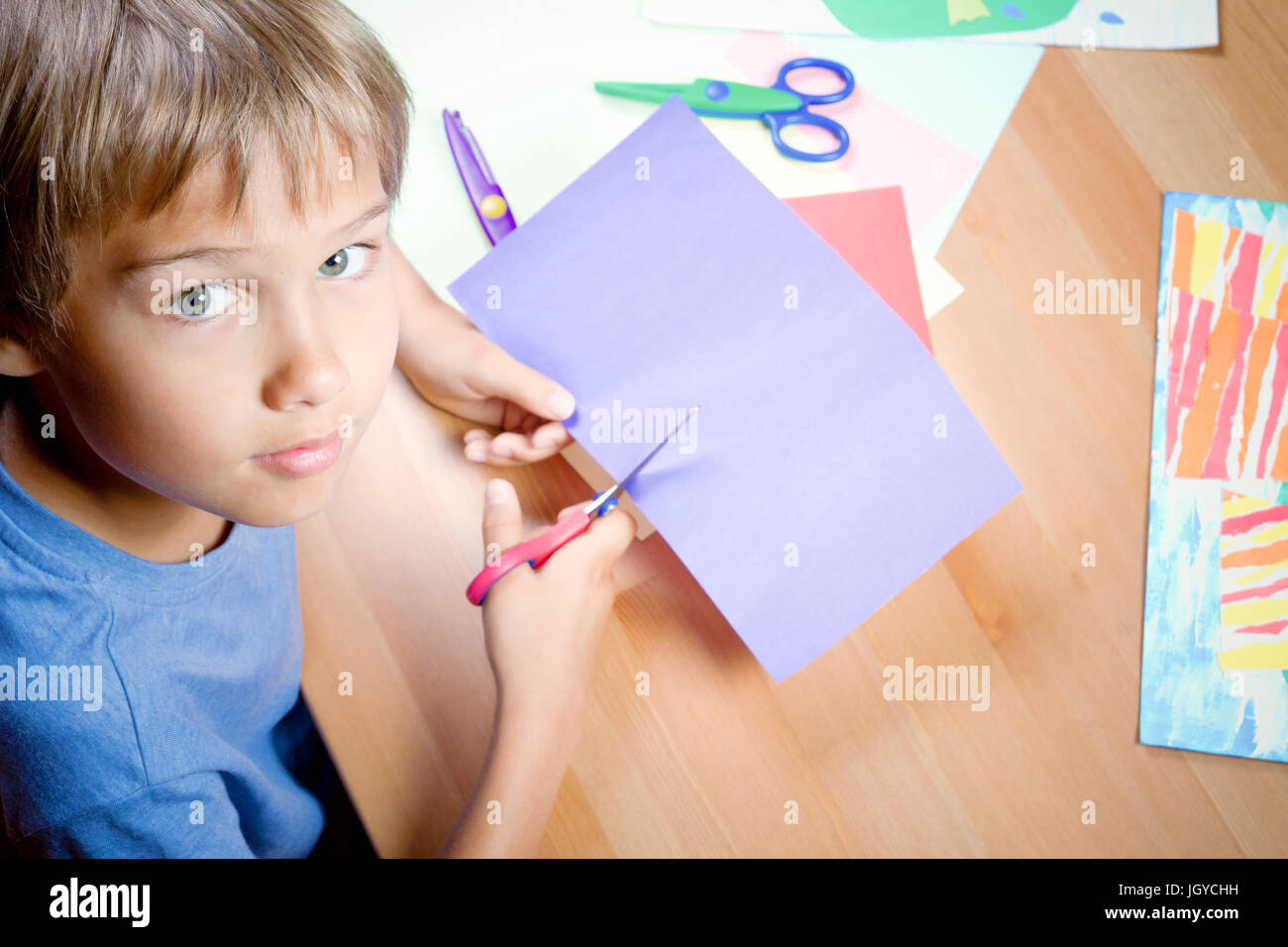 Child cutting colored paper with scissors at the table Stock Photo - Alamy