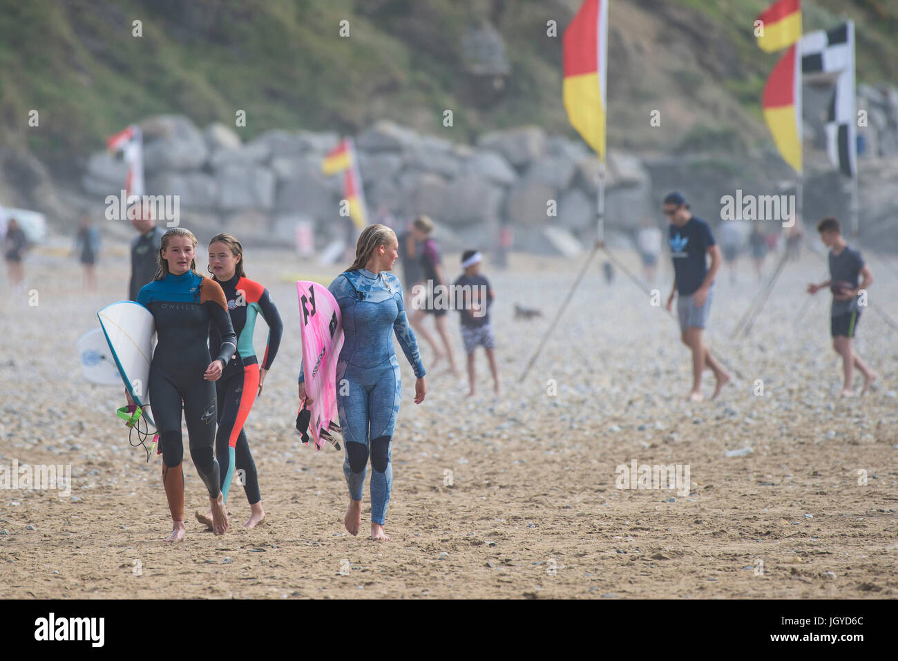 Surfing UK. Three young female surfers carrying their surfboards and ...