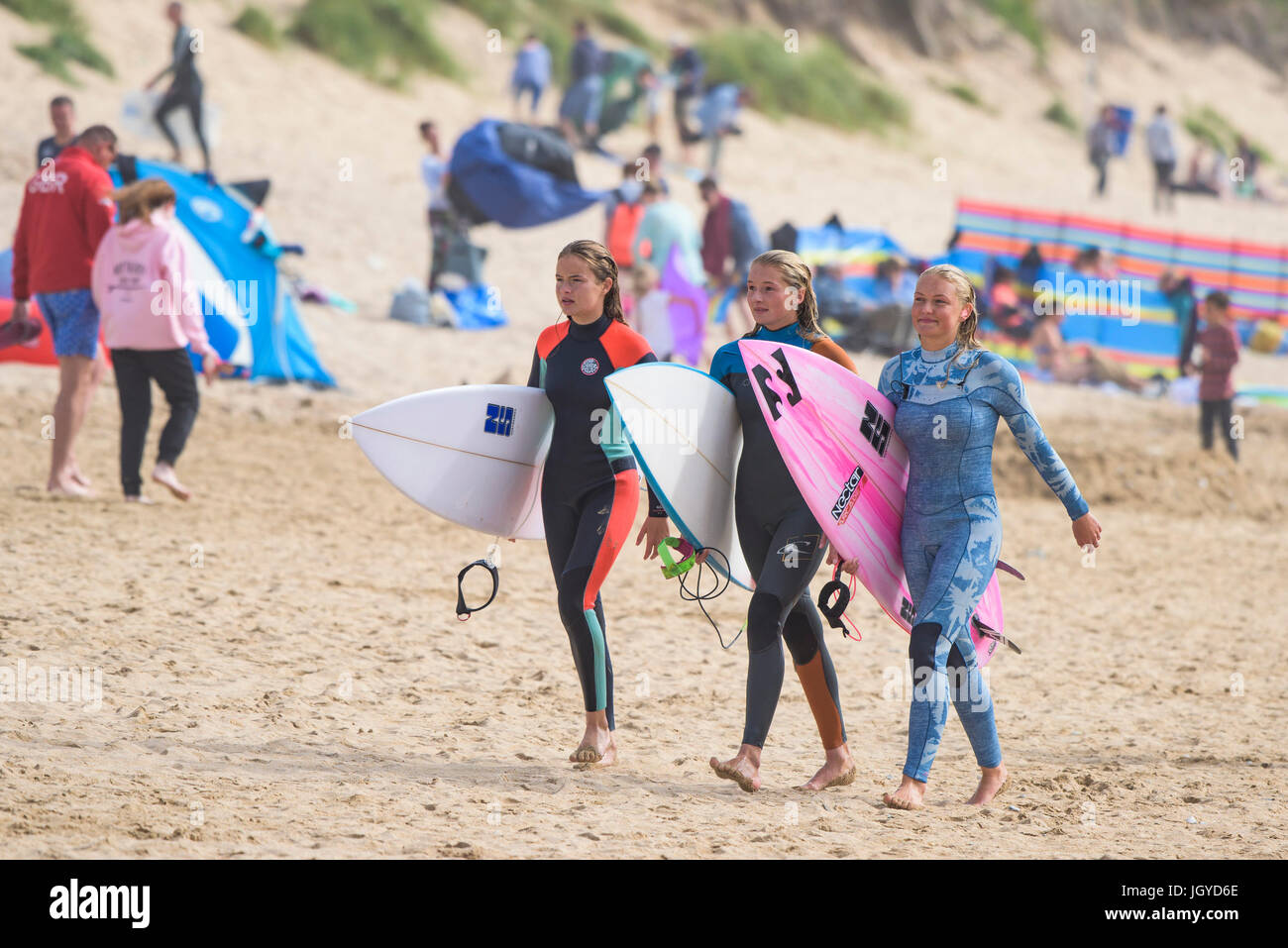 Surfing UK. Three young female surfers carrying their surfboards and ...