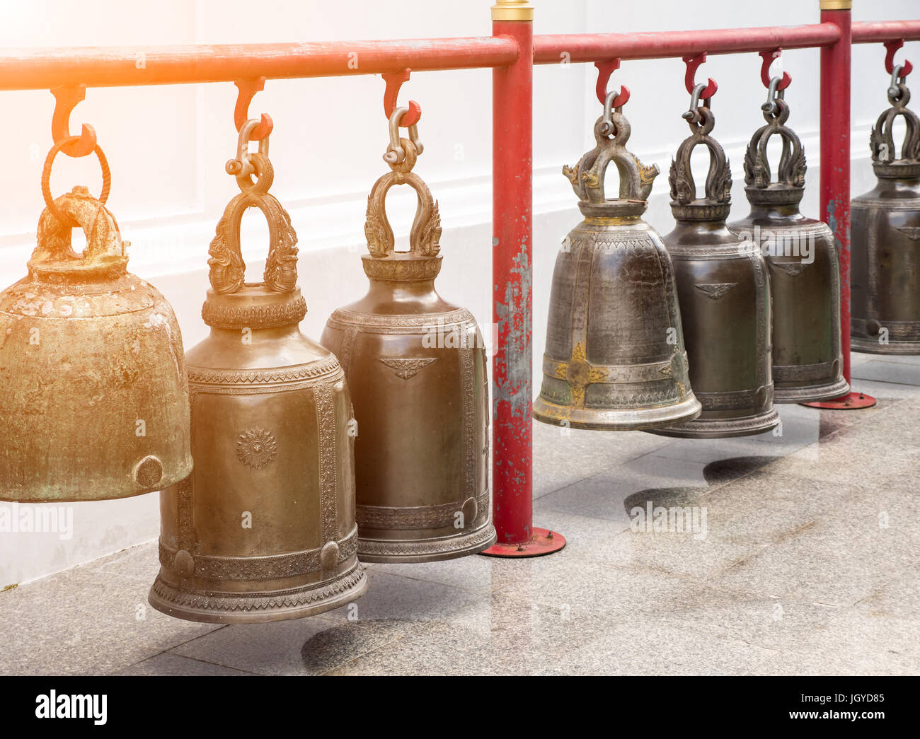 Brass bell row is hanging on the metal rail with the sunlight near the ...