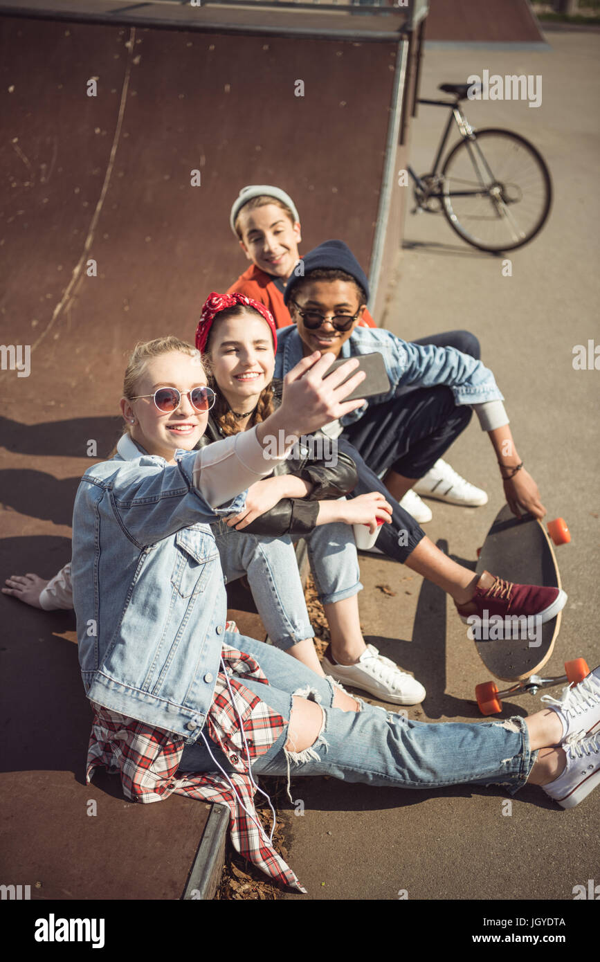 Smiling teenagers group taking hipster selfie while sitting together at ...