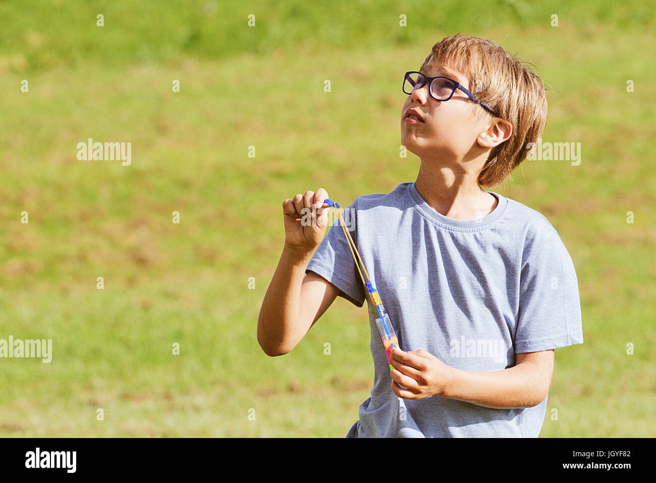 Child playing outdoors in a park with arrow helicopter elastic rocket ...