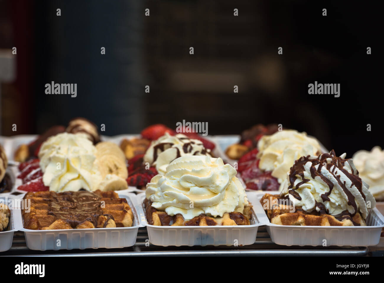 Rows of take away street waffles topped with strawberries chocolates ...