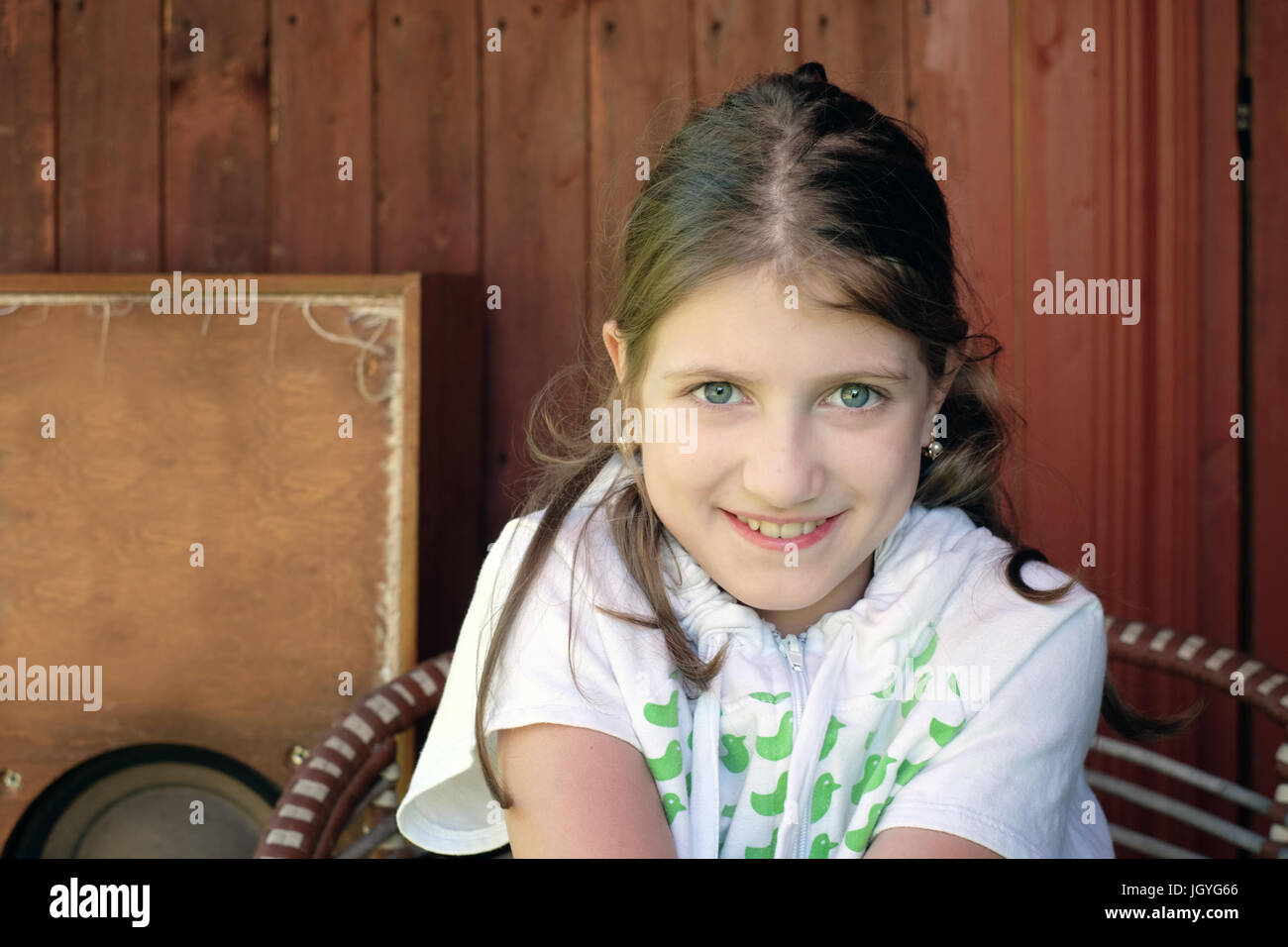Outdoor portrait of a teenage girl with a shy look in her face, wooden ...