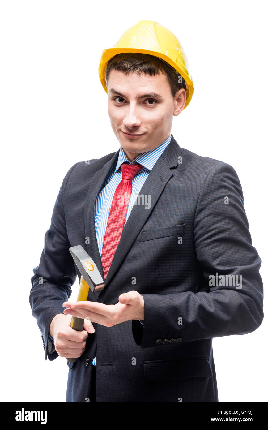 A man in a suit with a hammer is wearing a yellow protective helmet ...
