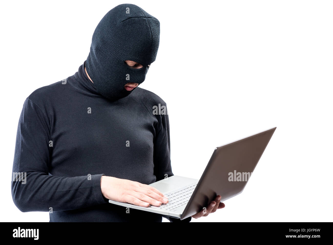 A hacker in black clothes and a mask with a laptop on a white ...