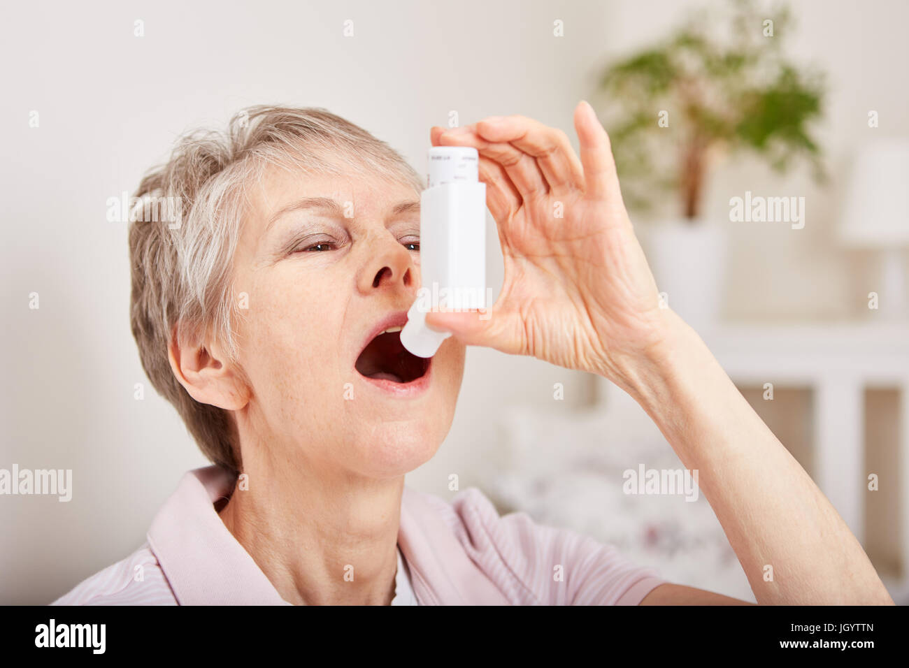 Senior woman holds inhaler for emergency labored breathing Stock Photo ...