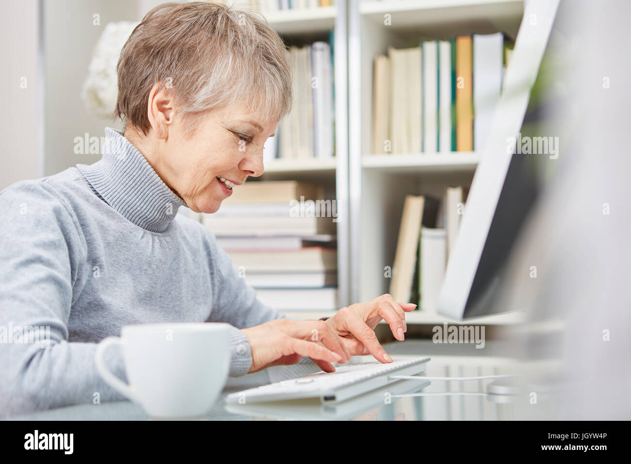 Senior woman writing and typing on keyboard from PC Stock Photo - Alamy