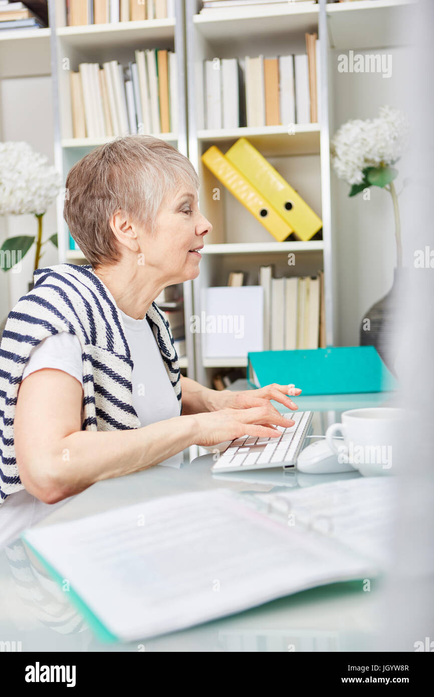 Woman as senior citizen writing and working with computer Stock Photo ...