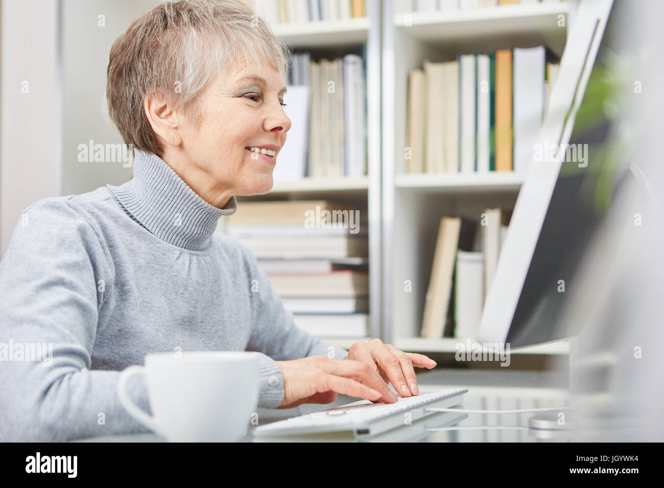 Senior citizen with computer looks at PC monitor Stock Photo - Alamy