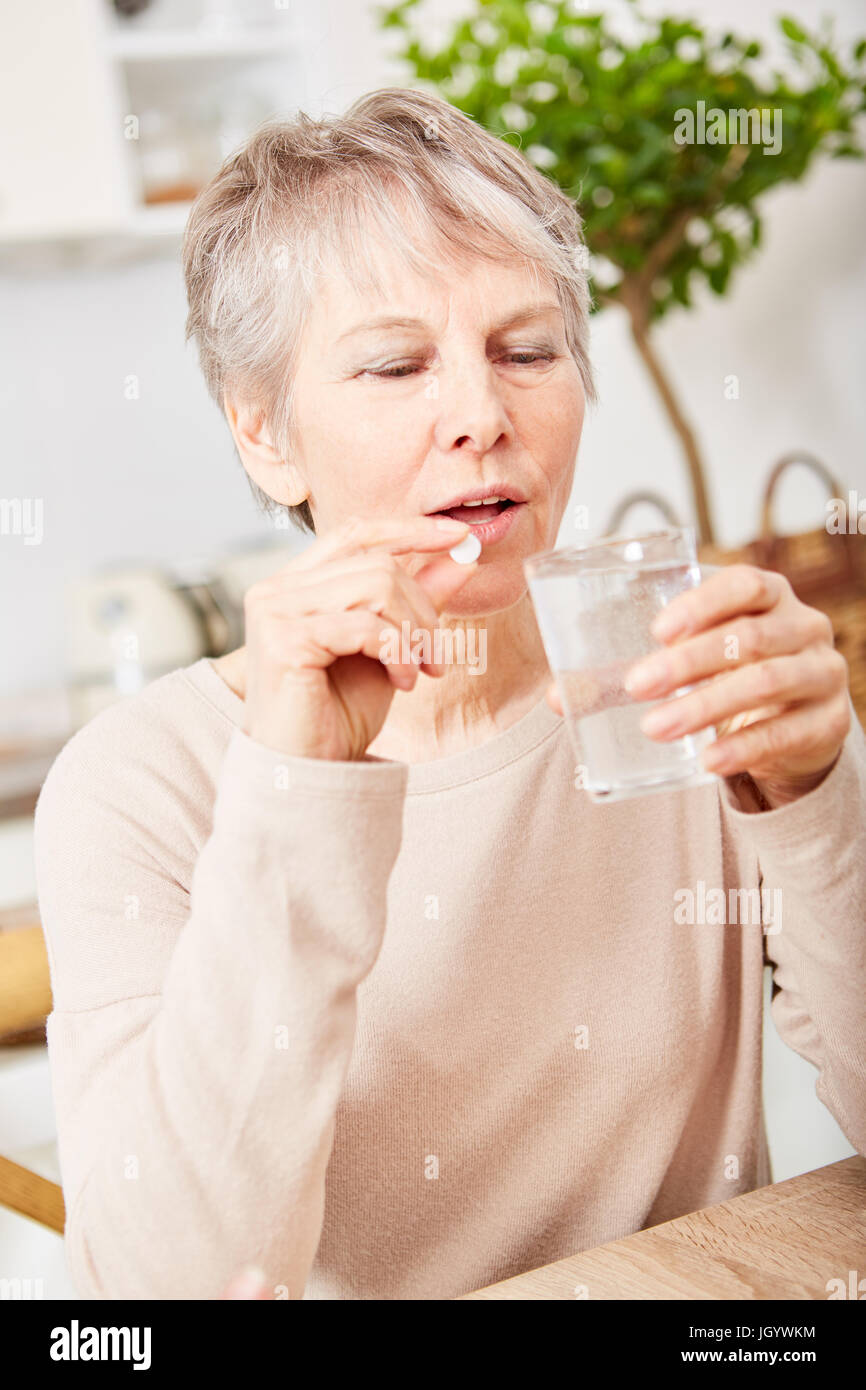Senior woman taking medicament tablets at home Stock Photo - Alamy