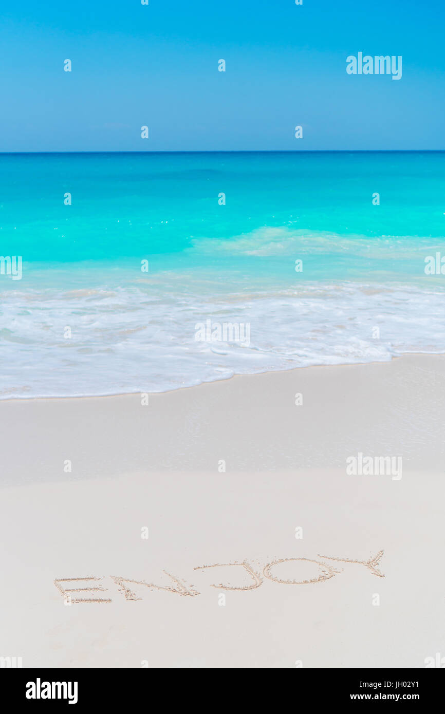 Word Enjoy handwritten on sandy beach with turquoise water Stock Photo ...