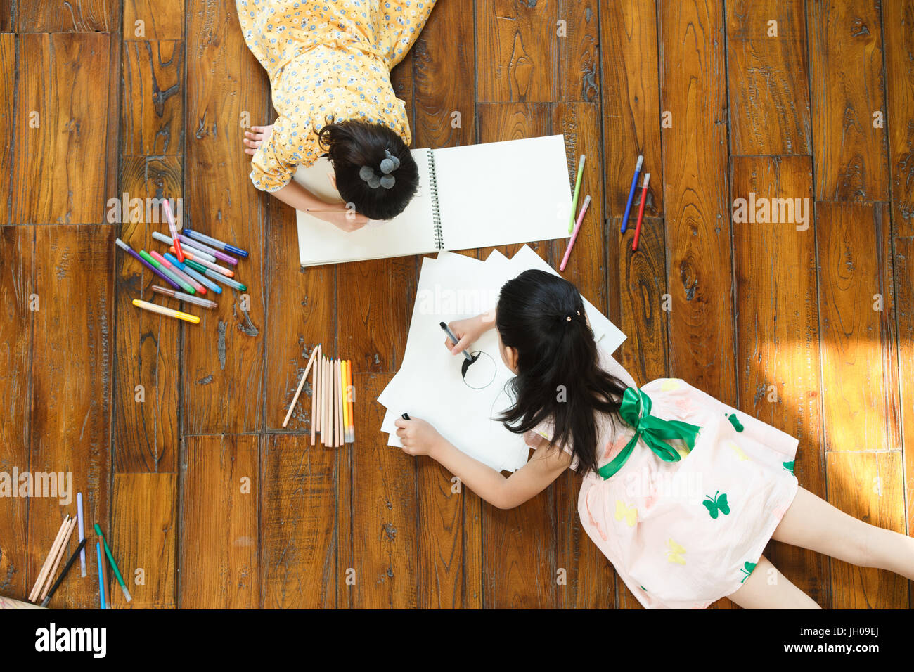 Two girls lying on floor drawing Stock Photo - Alamy