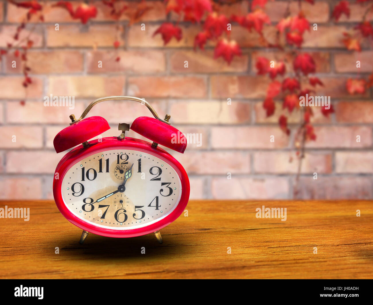 Old red alarm clock on wooden table In front of the brick wall Stock ...
