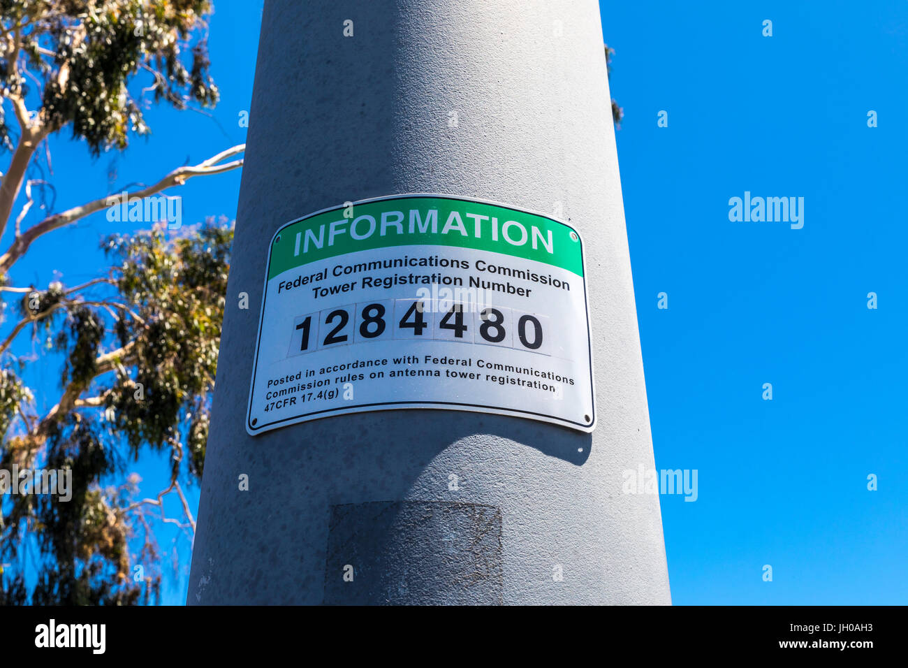 A cell phone tower in a parking lot of a group of retail stores with ...