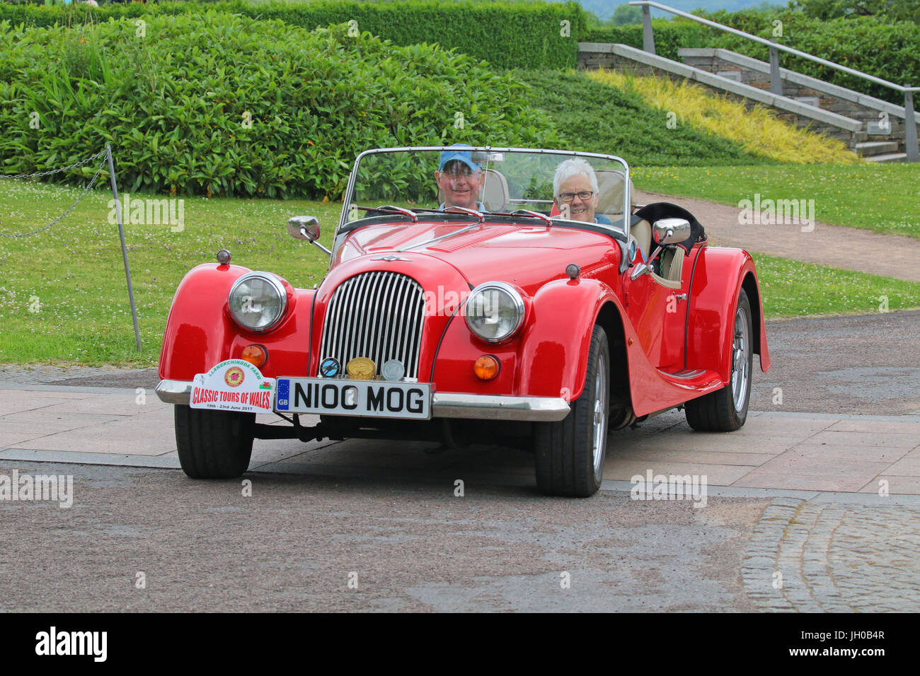 Smiling couple in red morgan car Stock Photo - Alamy