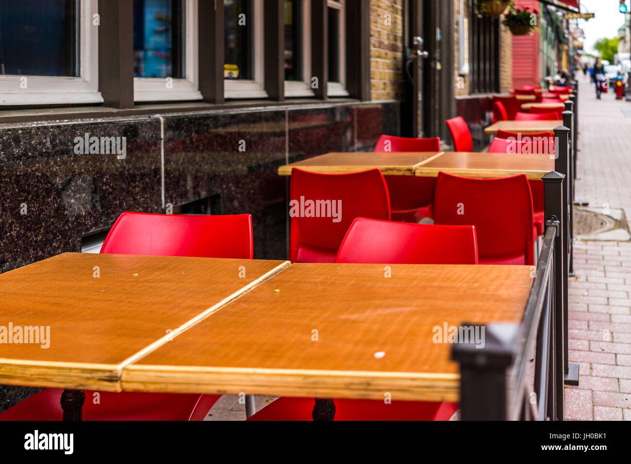 Wooden tables outside restaurant by sidewalk with cobblestone European ...