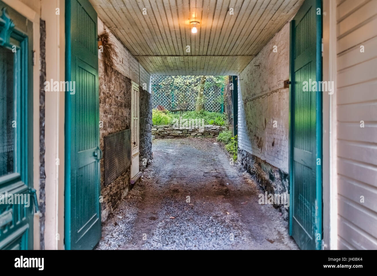 Old narrow dark brick white and green alleyway with path to garden ...