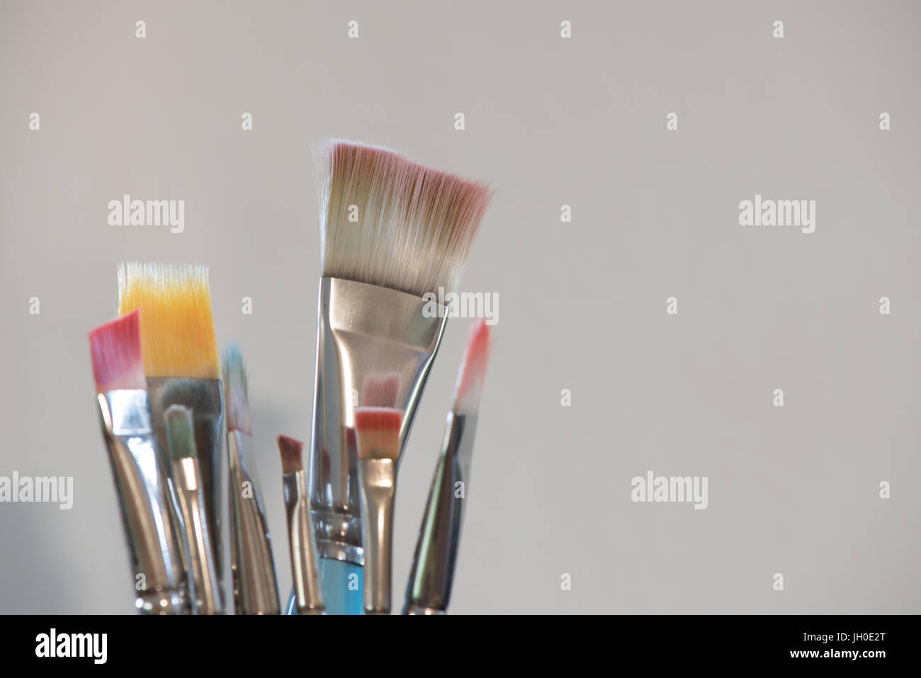 Paintbrush stained with colour and ready to use with a plain background ...