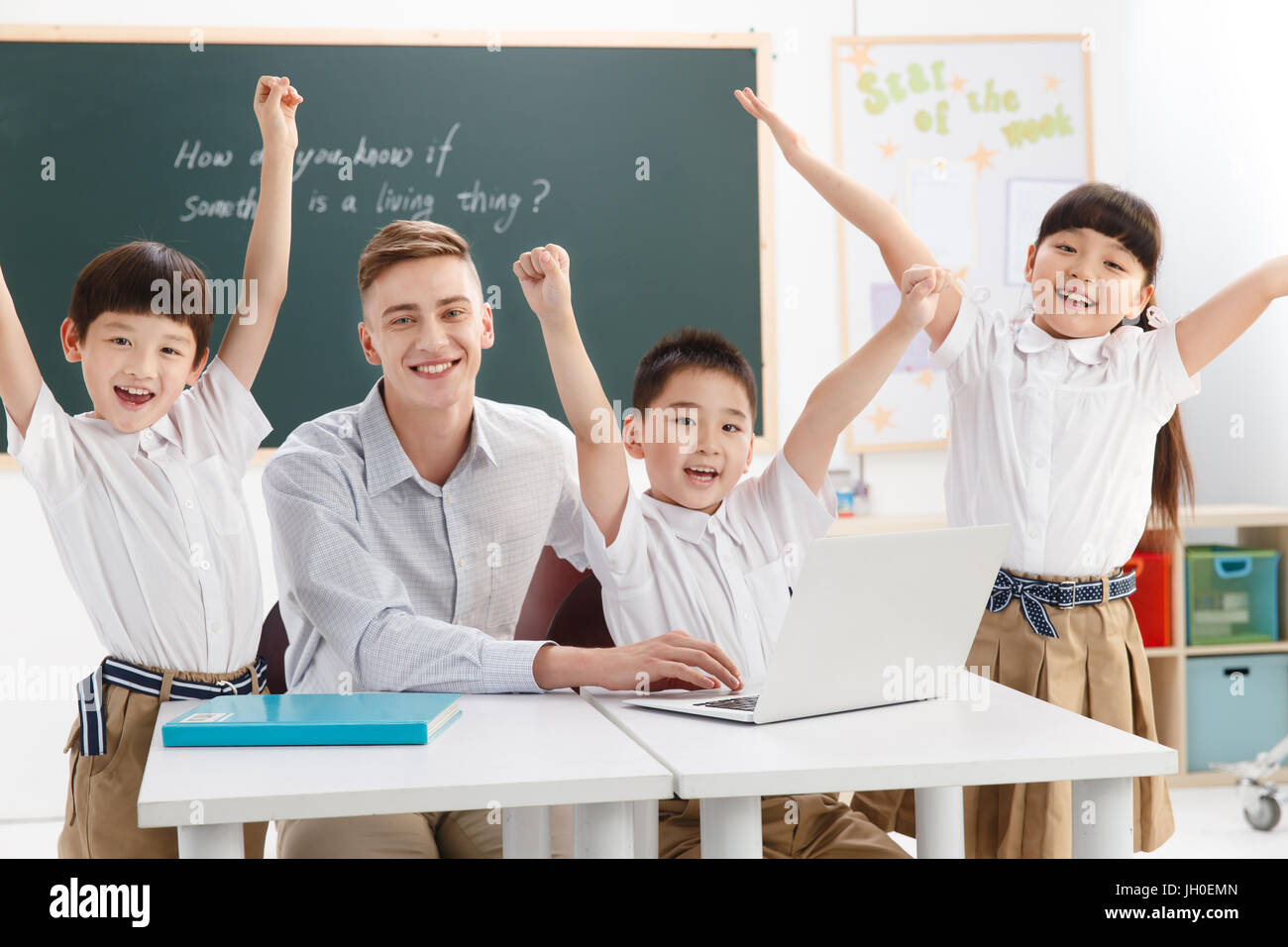 Male teacher helping students study in classroom Stock Photo - Alamy