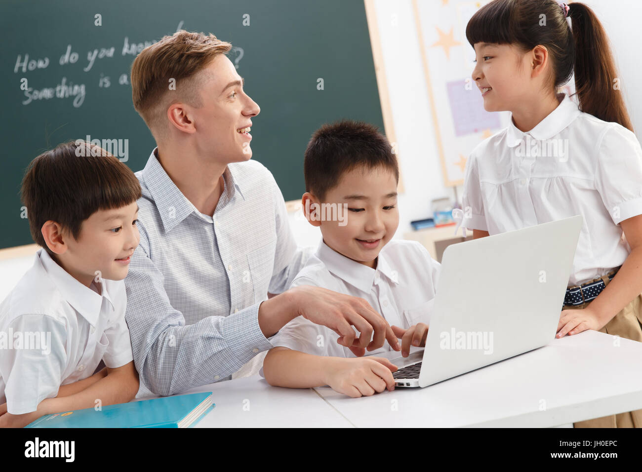 Male teacher helping students study in classroom Stock Photo - Alamy