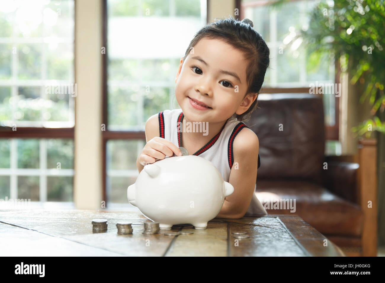 Girl dropping coin into saving box Stock Photo - Alamy