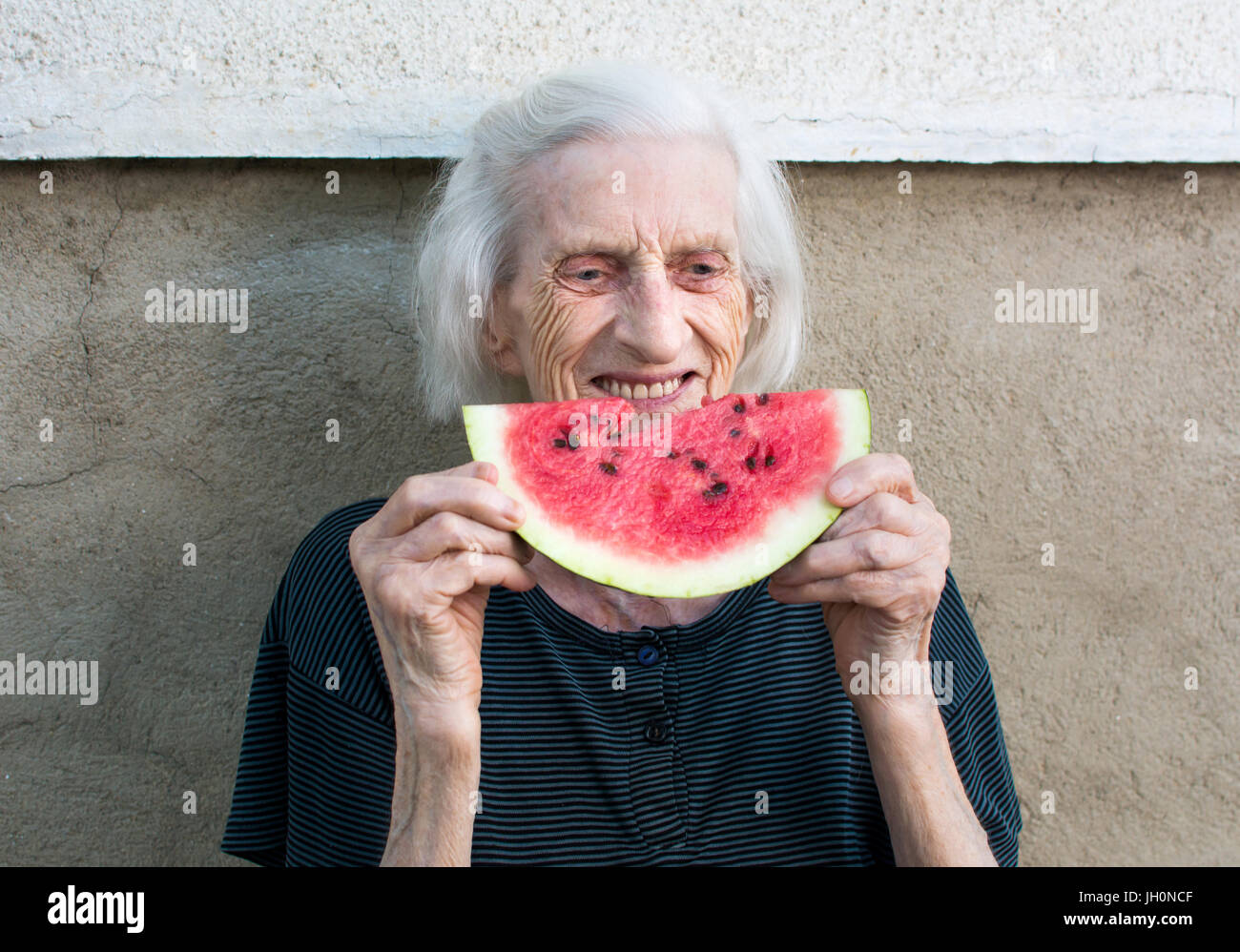Cheerful grandma eating watermelon fruit in the backyard Stock Photo ...