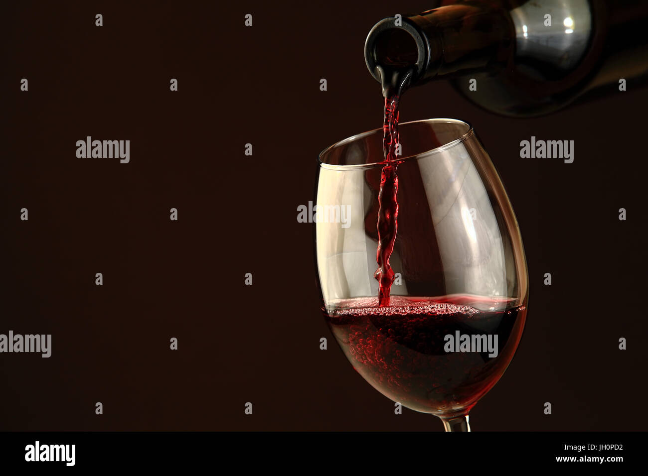 Red wine pouring into a glass close-up. Flowing wine from bottle Stock ...
