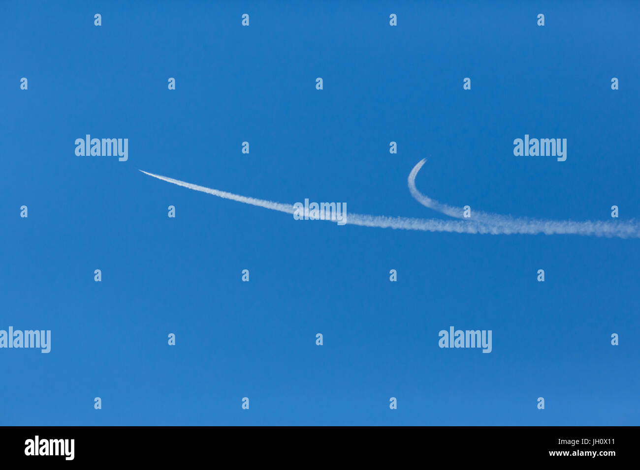 two splitting white jet trails in blue sky flying curves Stock Photo ...