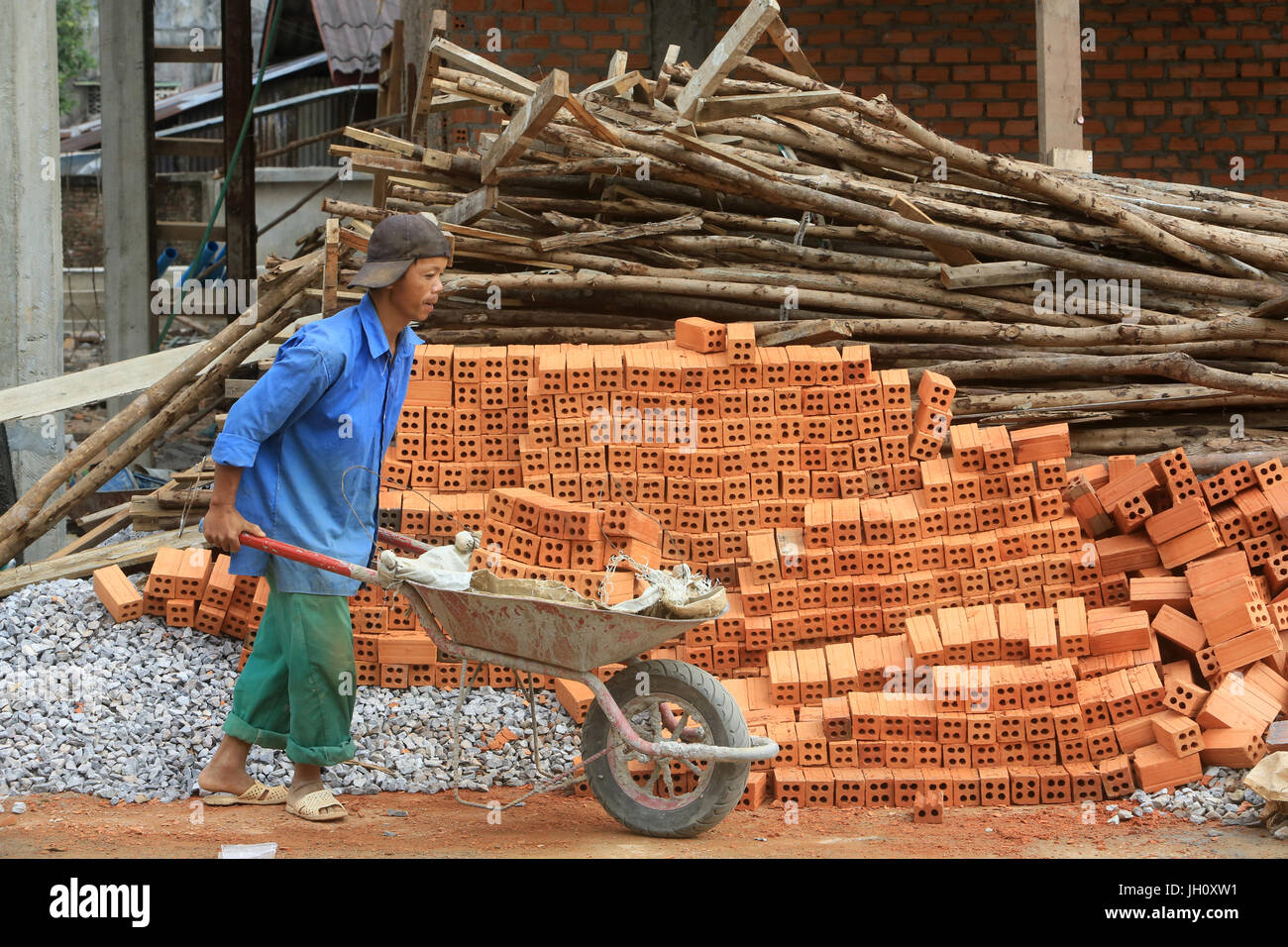 Man carrying bricks in a wheelbarrow. Construction site. Laos Stock ...
