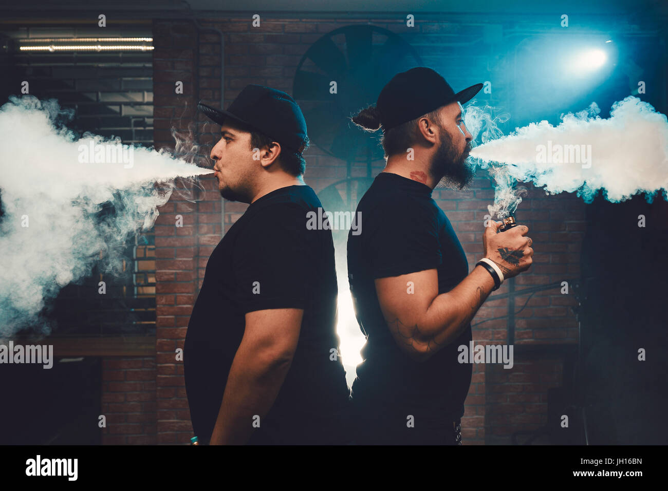 Two men vaping in an authentic room with brick walls. Vaping an ...