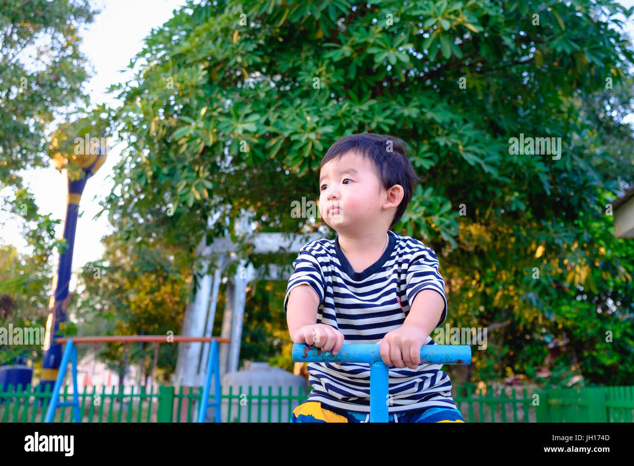 Sad kid play teeter-totter at the playground under sunlight, in ...
