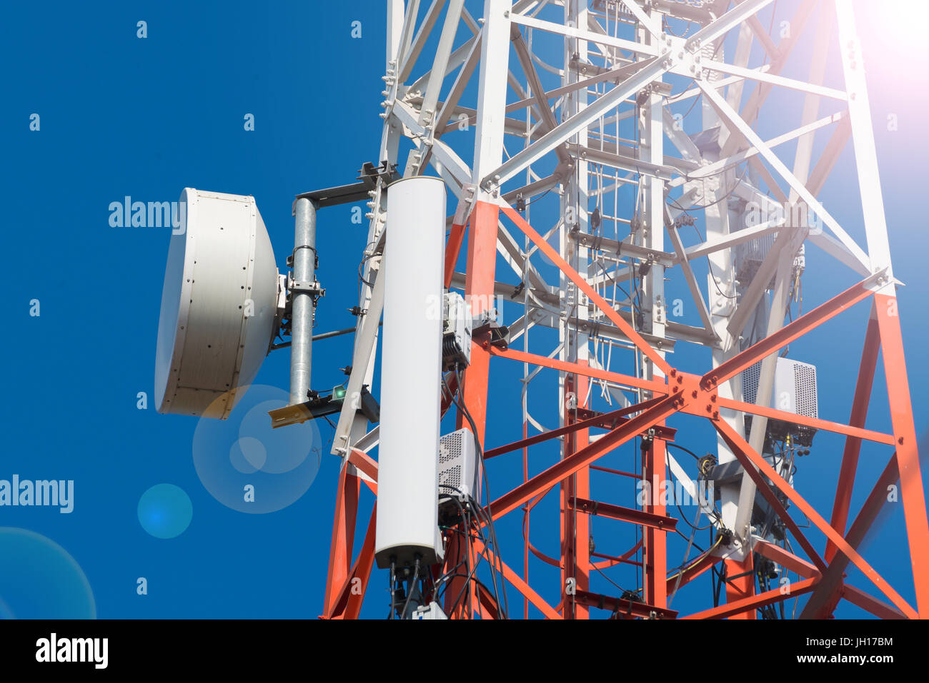 Mobile phone communication antenna tower with satellite dish on blue ...