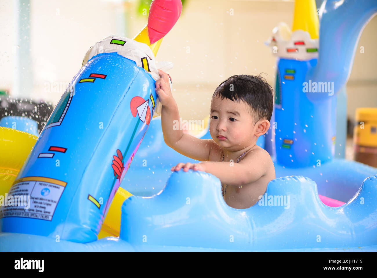 Sad Asian kid playing alone in inflatable baby pool. Boy swim and ...