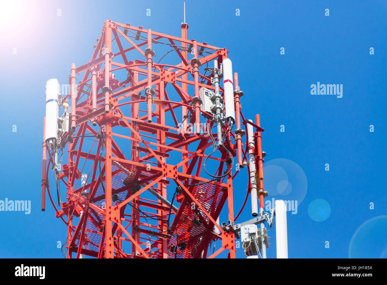 Mobile phone communication antenna tower with satellite dish on blue sky background ...