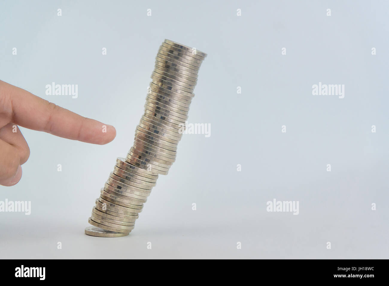 Finger pushing a pile of coins, column of coins falls , business crisis ...