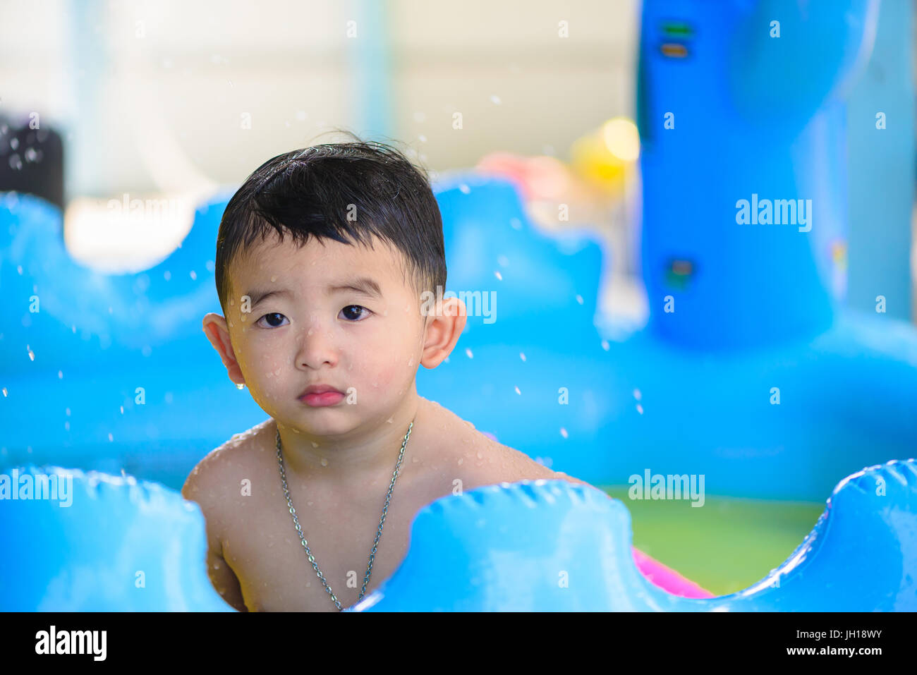 Sad Asian kid playing alone in inflatable baby pool. Boy swim and ...