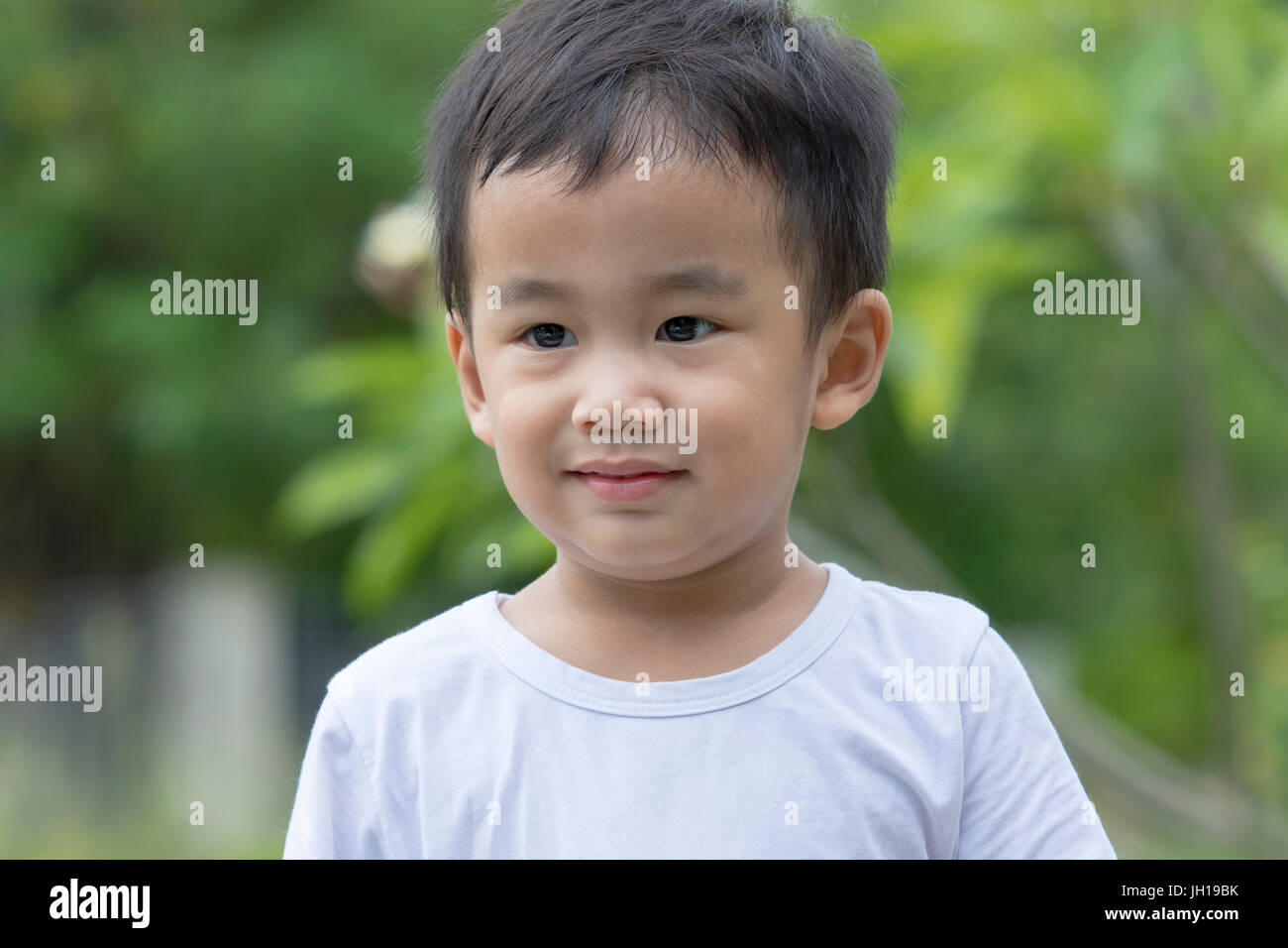 portrait head shot of asian children smiling face against green blur ...