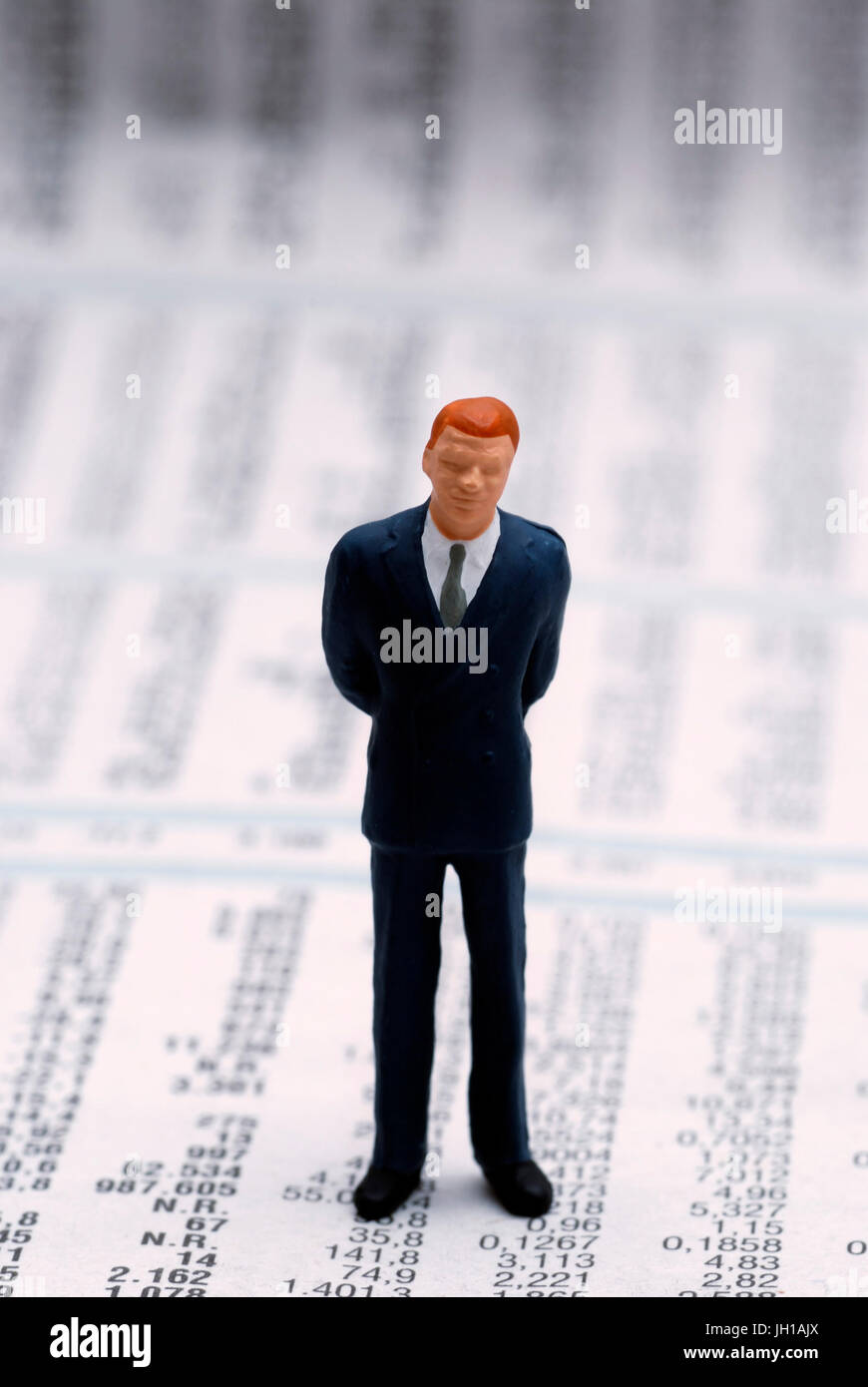 businessman miniature figurine standing on financial data, economy ...