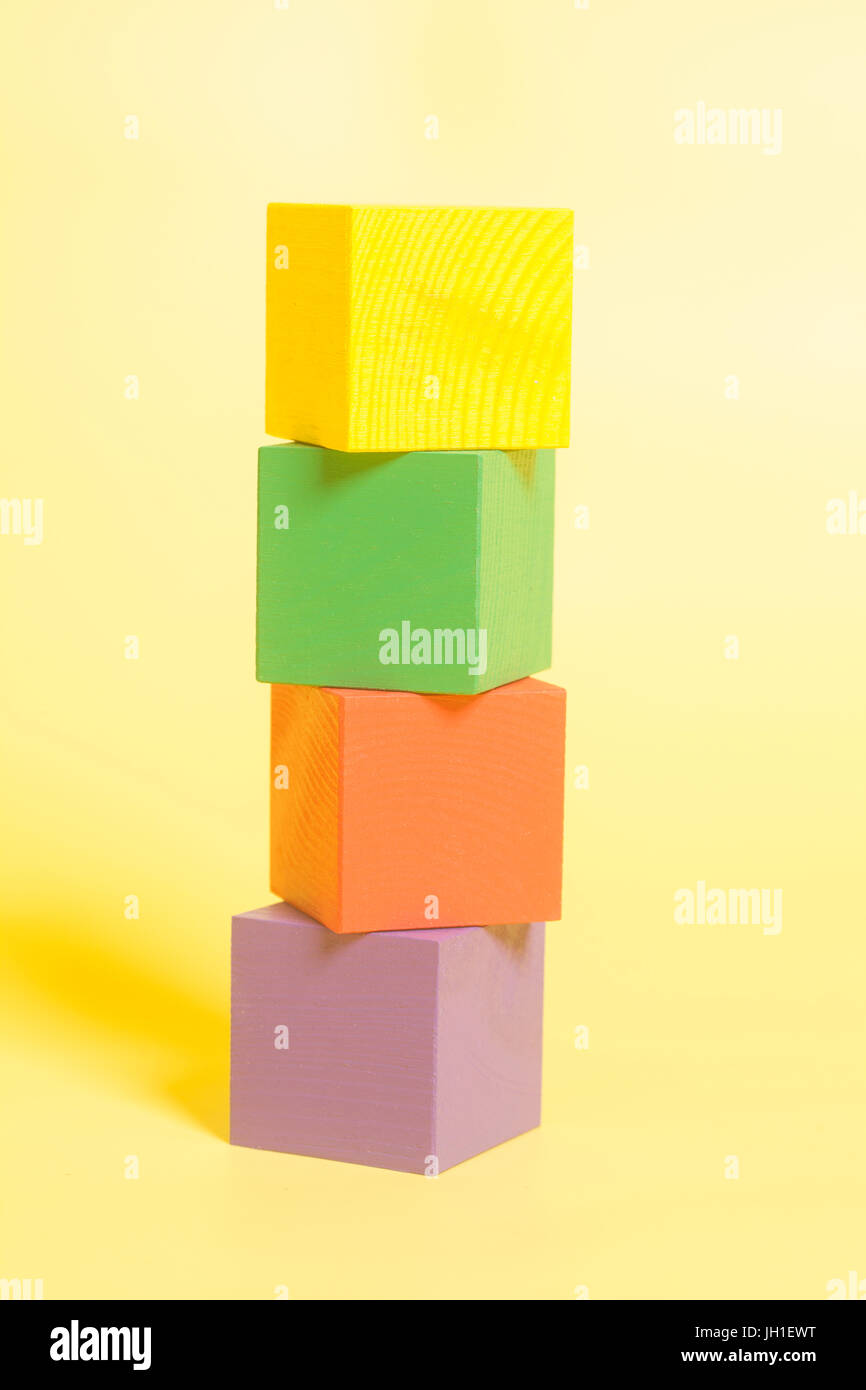 Coloured wooden cubes on yellow background Stock Photo - Alamy