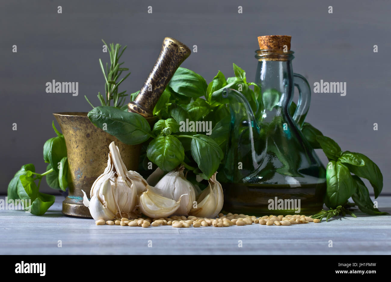 Old copper mortar with olive oil, garlic, green basil and pine nuts ...