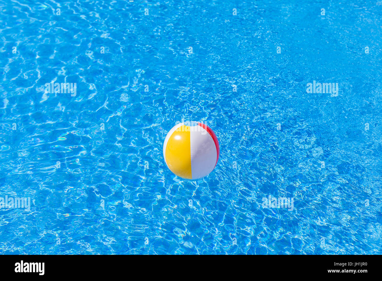 Inflatable beach ball floating in an outdoor swimming pool Stock Photo ...